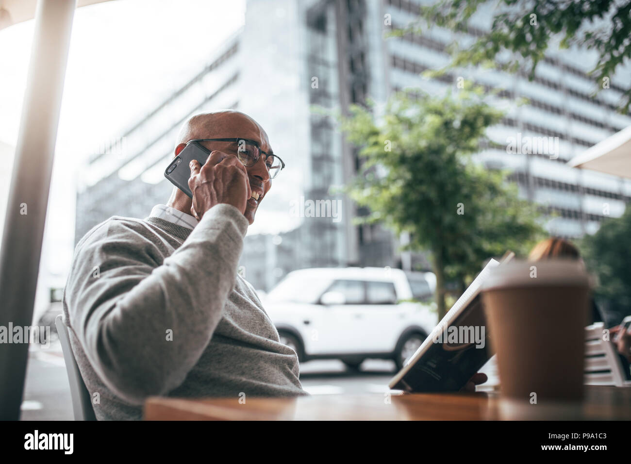 businessman in sweater talking on cell phone while reading a book ...