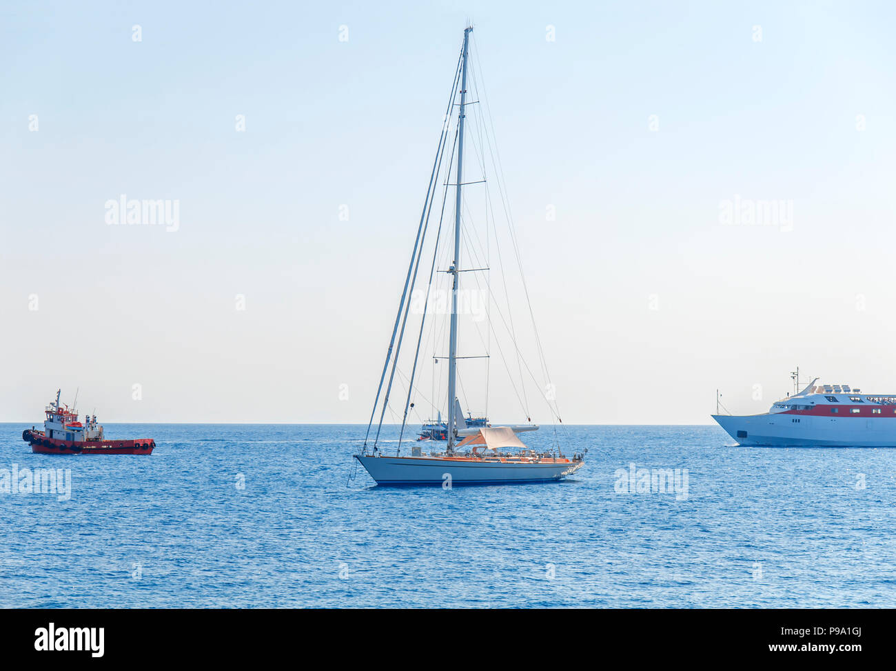 One fancy boat docked at sea and three boat passing by with clean blue ...