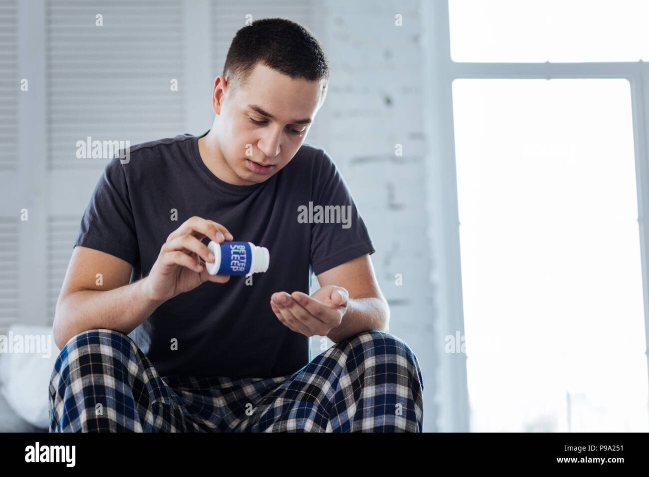 Unsmiling man taking some sleeping pills Stock Photo - Alamy