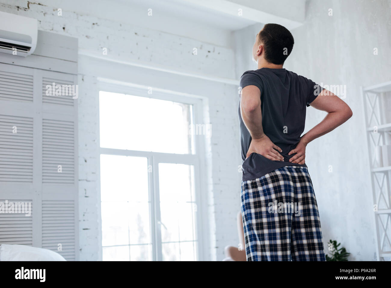 Well-built man touching his back Stock Photo - Alamy