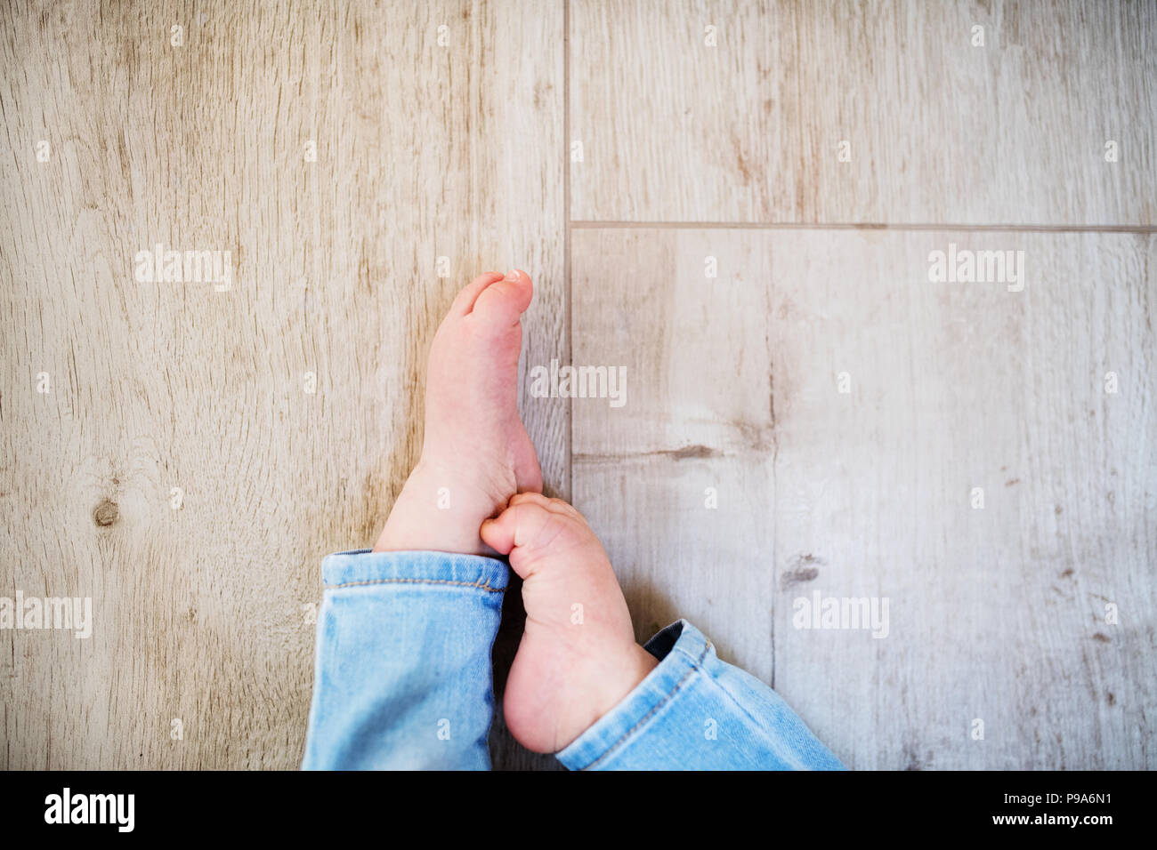 A baby feet of an unrecognizable boy sitting on the floor at home. Copy ...