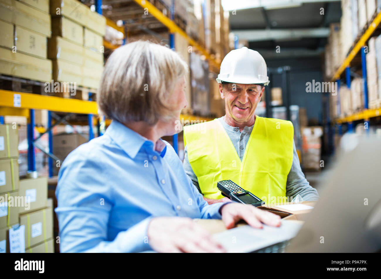 Senior woman manager and man worker working in a warehouse Stock Photo ...