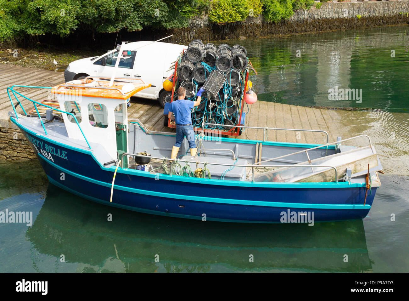 fisherman loading shrimp pots or shrimp traps onto his fishing boat ...