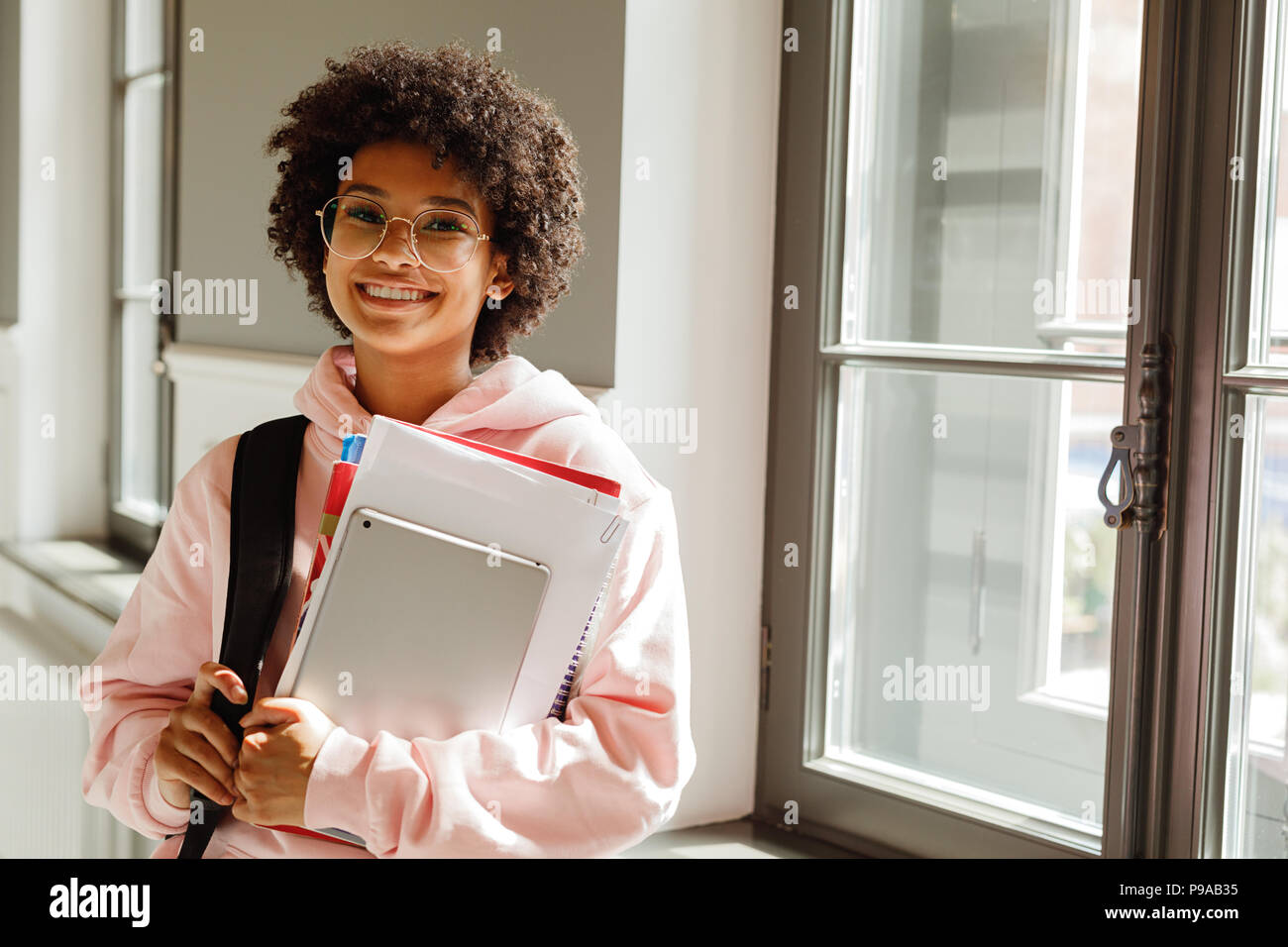 University student with books standing indoors at window Stock Photo ...
