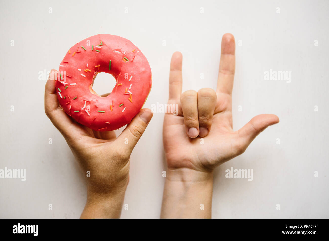 A female hand holds a donut on a white background. The other hand shows ...