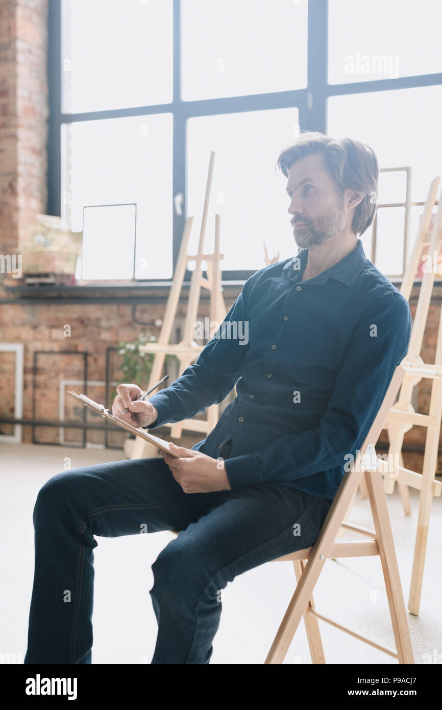 Warm toned full length portrait of pensive mature man sitting alone in ...