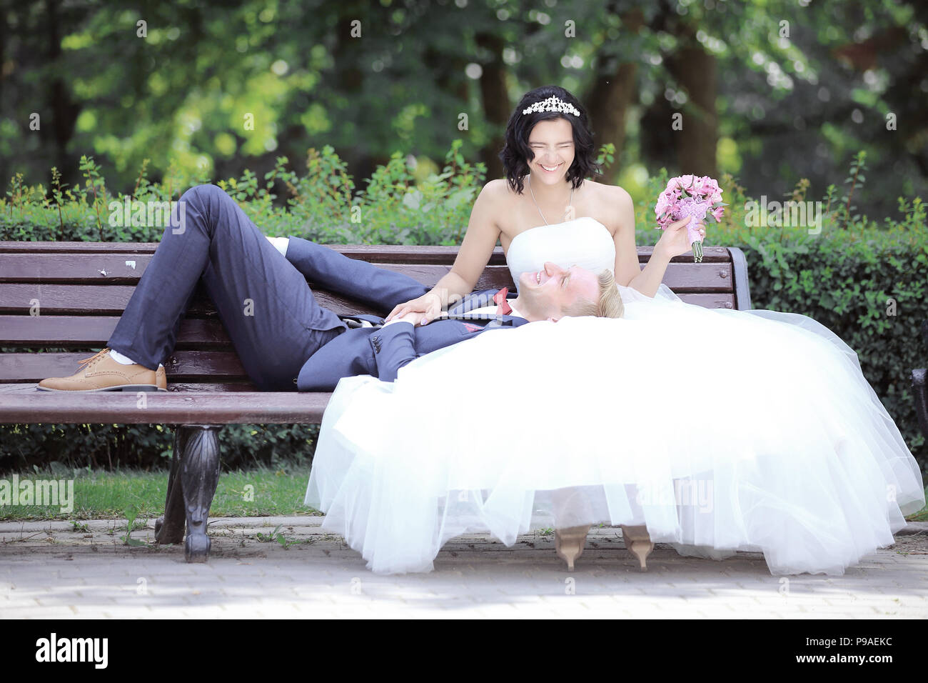 bride and groom resting on a bench Stock Photo - Alamy
