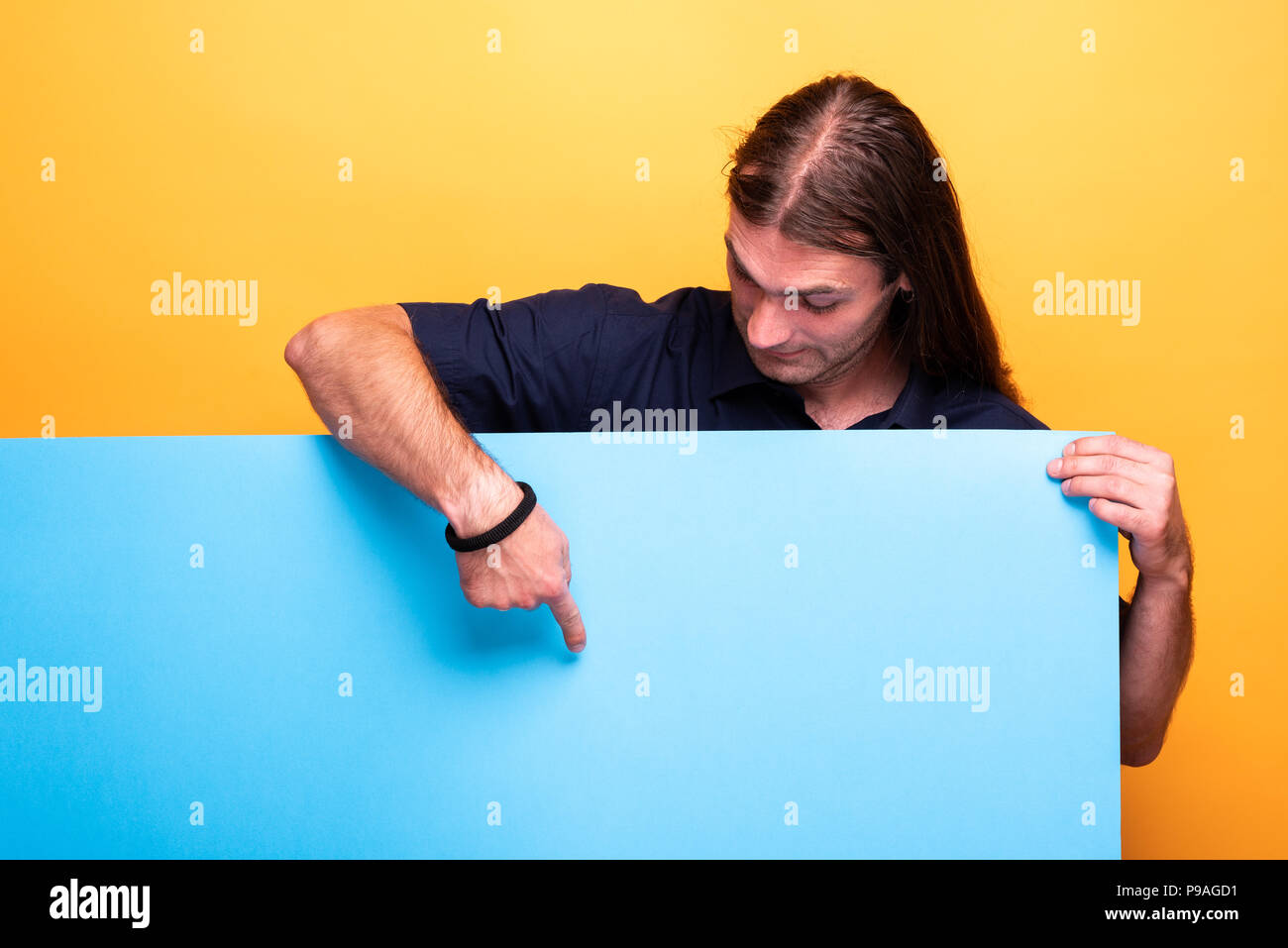 Man looking down while pointing at cardboard banner Stock Photo - Alamy