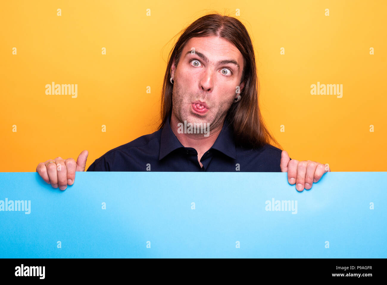 Funny grimace on man face while displayng a blue cardboard Stock Photo ...
