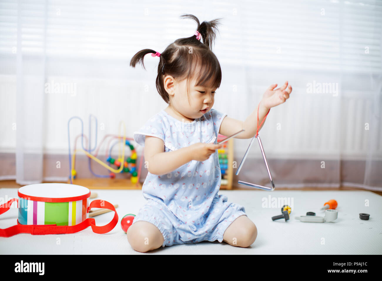 baby girl play triangle at home Stock Photo - Alamy