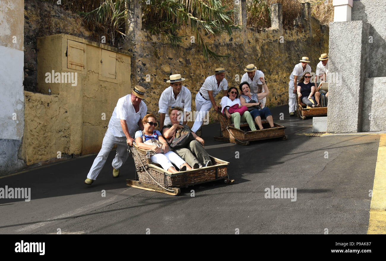 Tourists enjoying a ride downhill on a traditional wicker basket ...