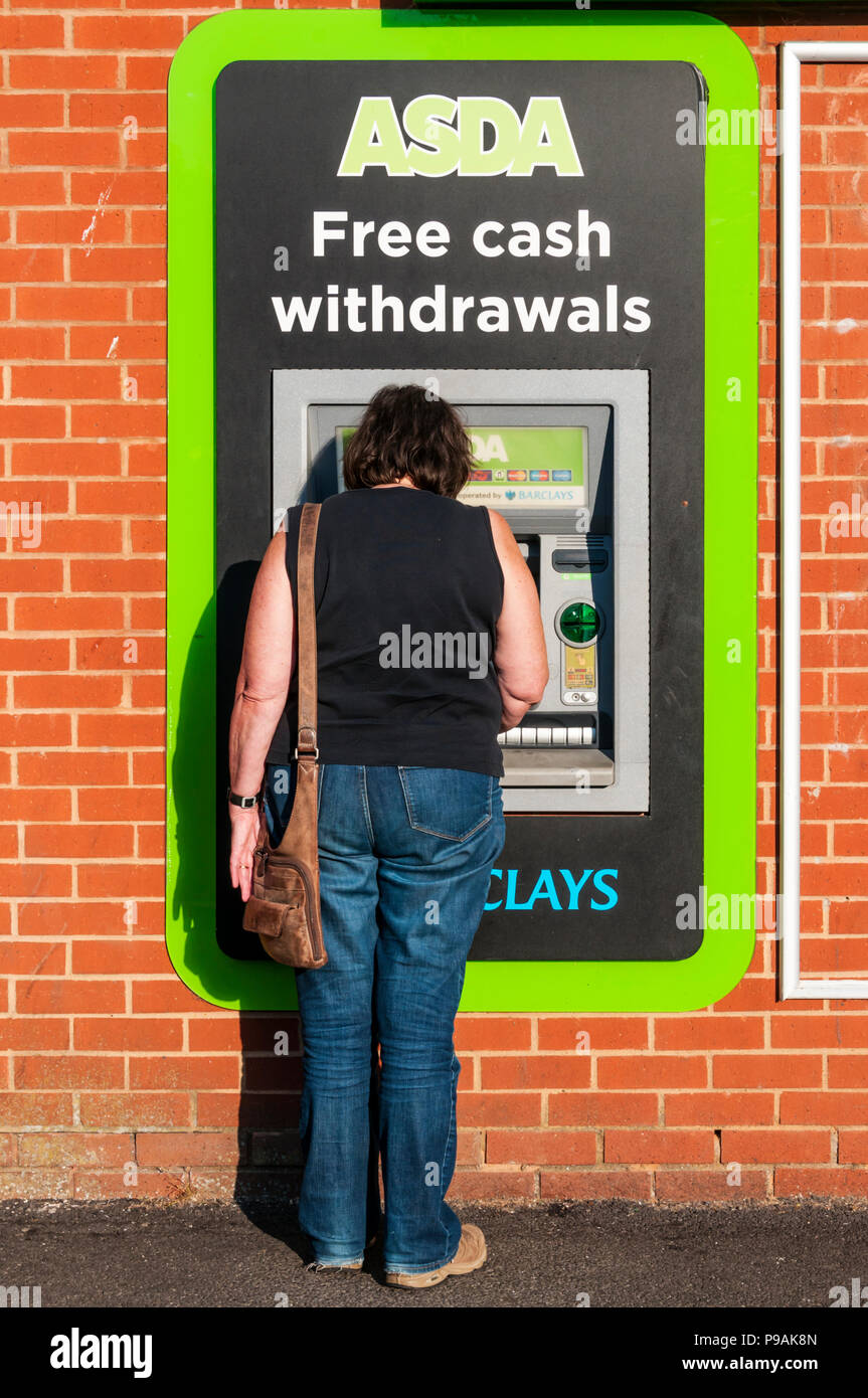 A woman using a free cash machine outside an Asda supermarket Stock ...