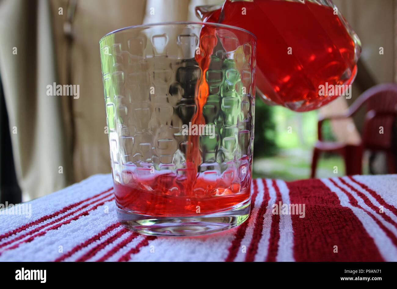 Red Fruit Drink Pouring into Glass Outside Stock Photo - Alamy