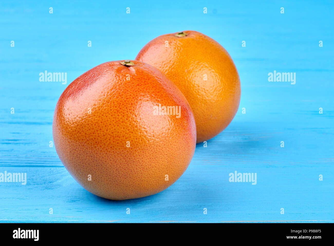 Close up delicious grapefruits on blue surface. Ripe organic ...