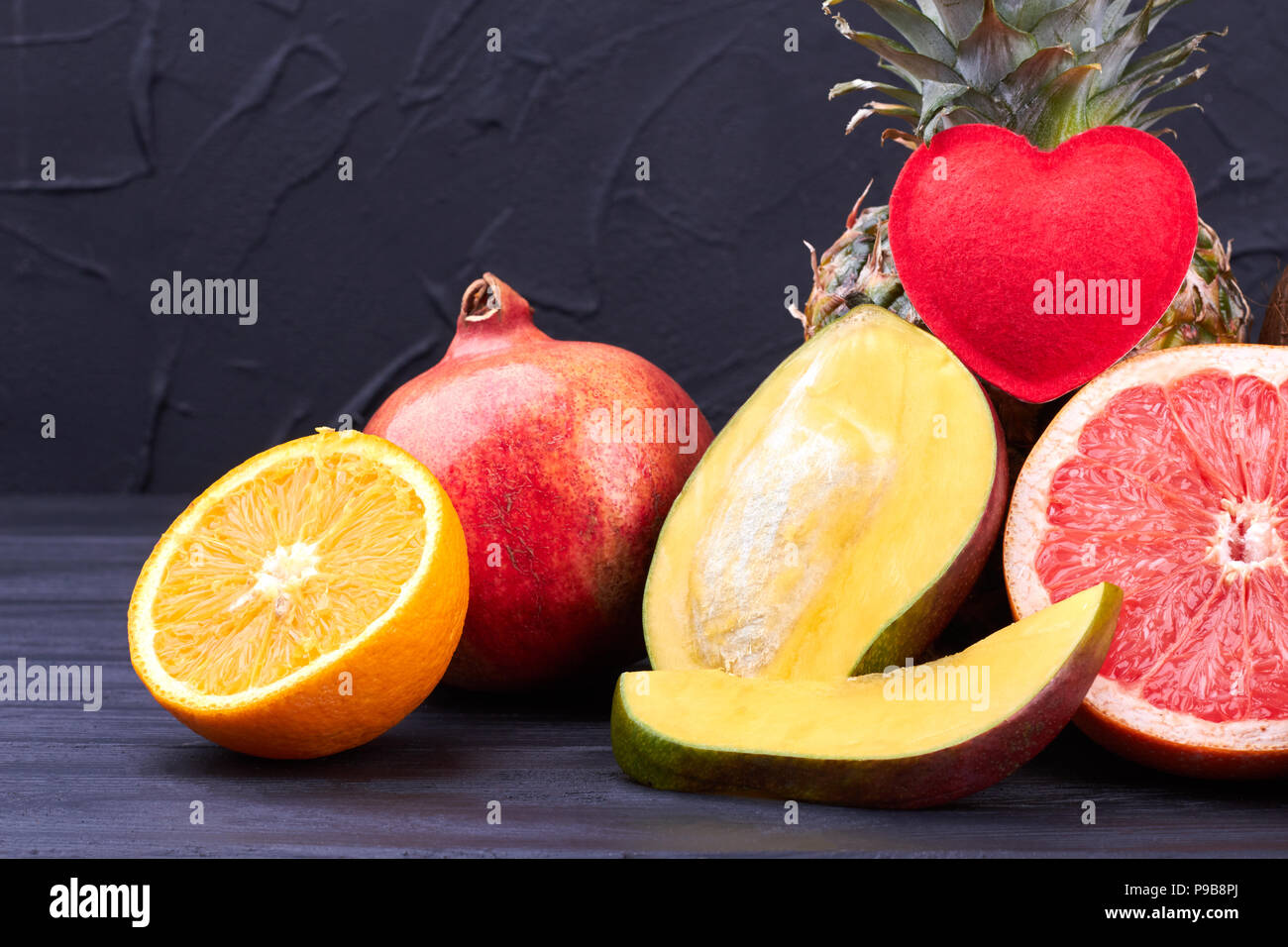 Mix of tropical fruits on black background. Whole pomegranate ...