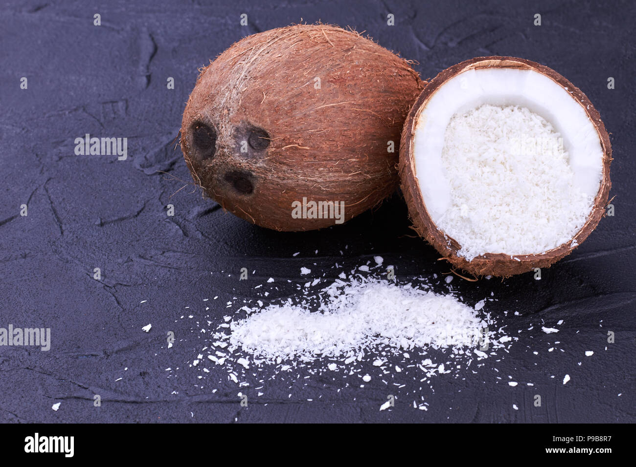 Fresh ripe coconuts on black slate. Heap of coconut flakes on dark ...