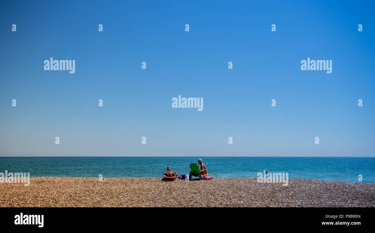Sunbathers on the shingle beach enjoying a glorious July summer day in ...