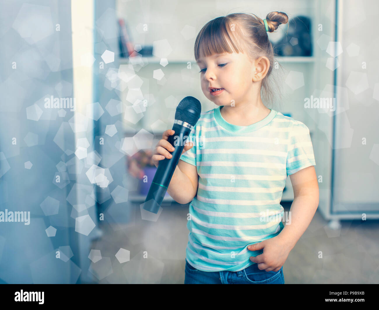Cute little girl using spoon as microphone at home Stock Photo - Alamy