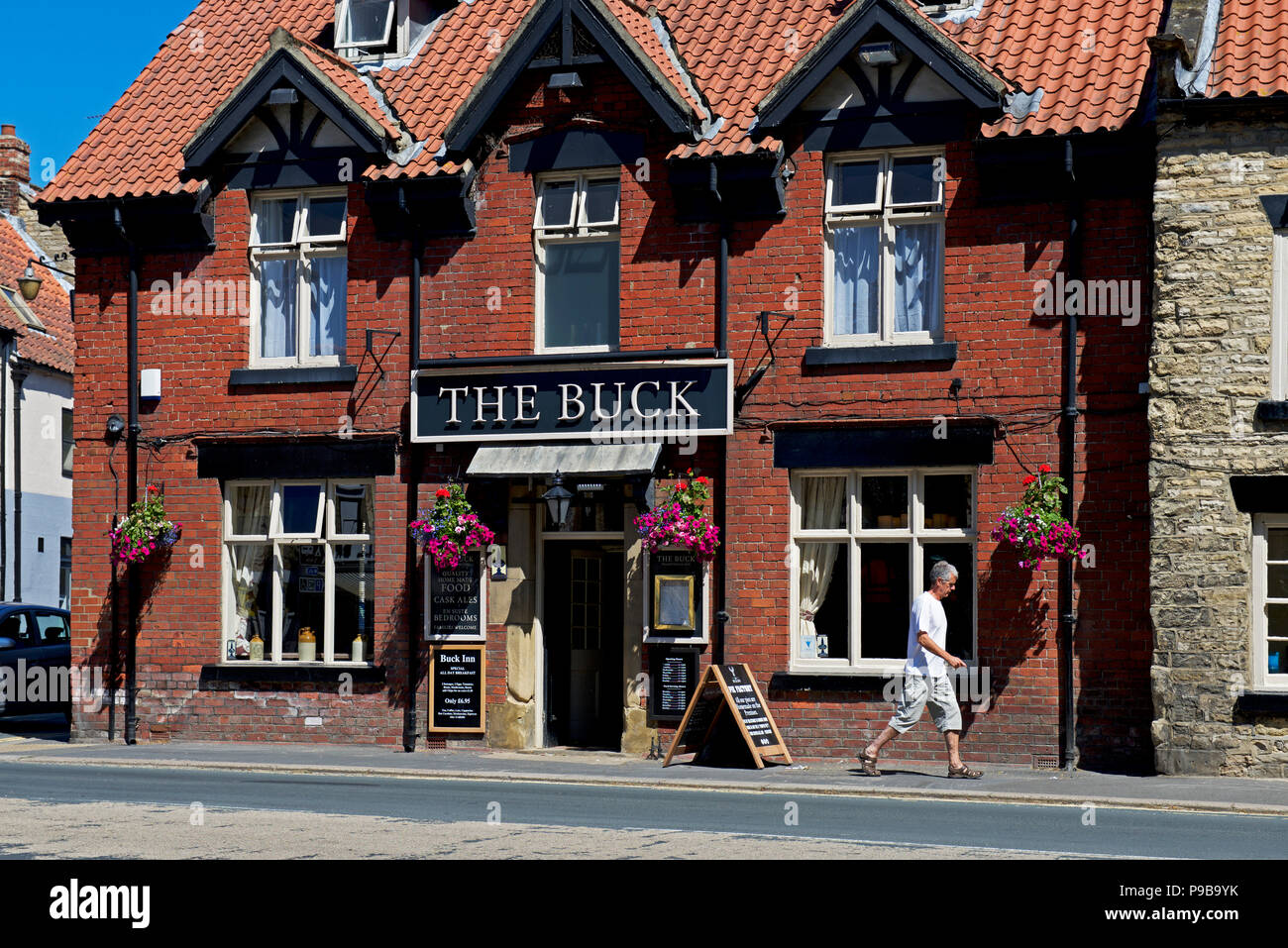 Man walking past the Buck Inn, Thornton-le-Dale, North Yorkshire ...