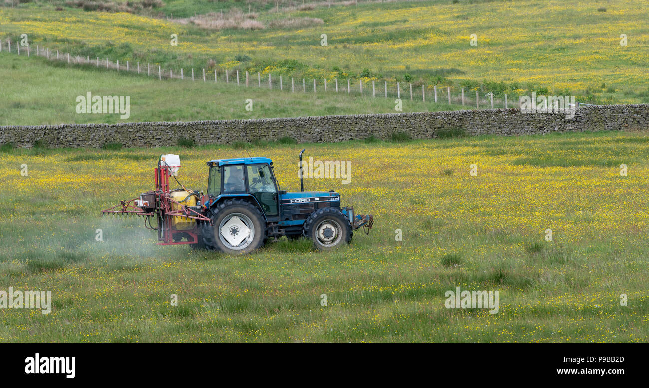 Farmer spraying weeds with a tractor mounted sprayer in a pasture ...