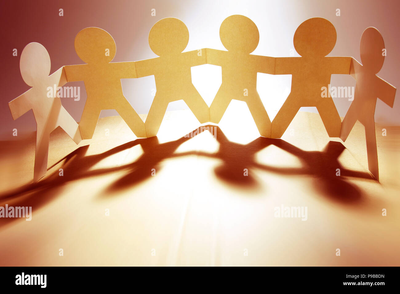 Team of paper chain people in a row holding hands Stock Photo - Alamy