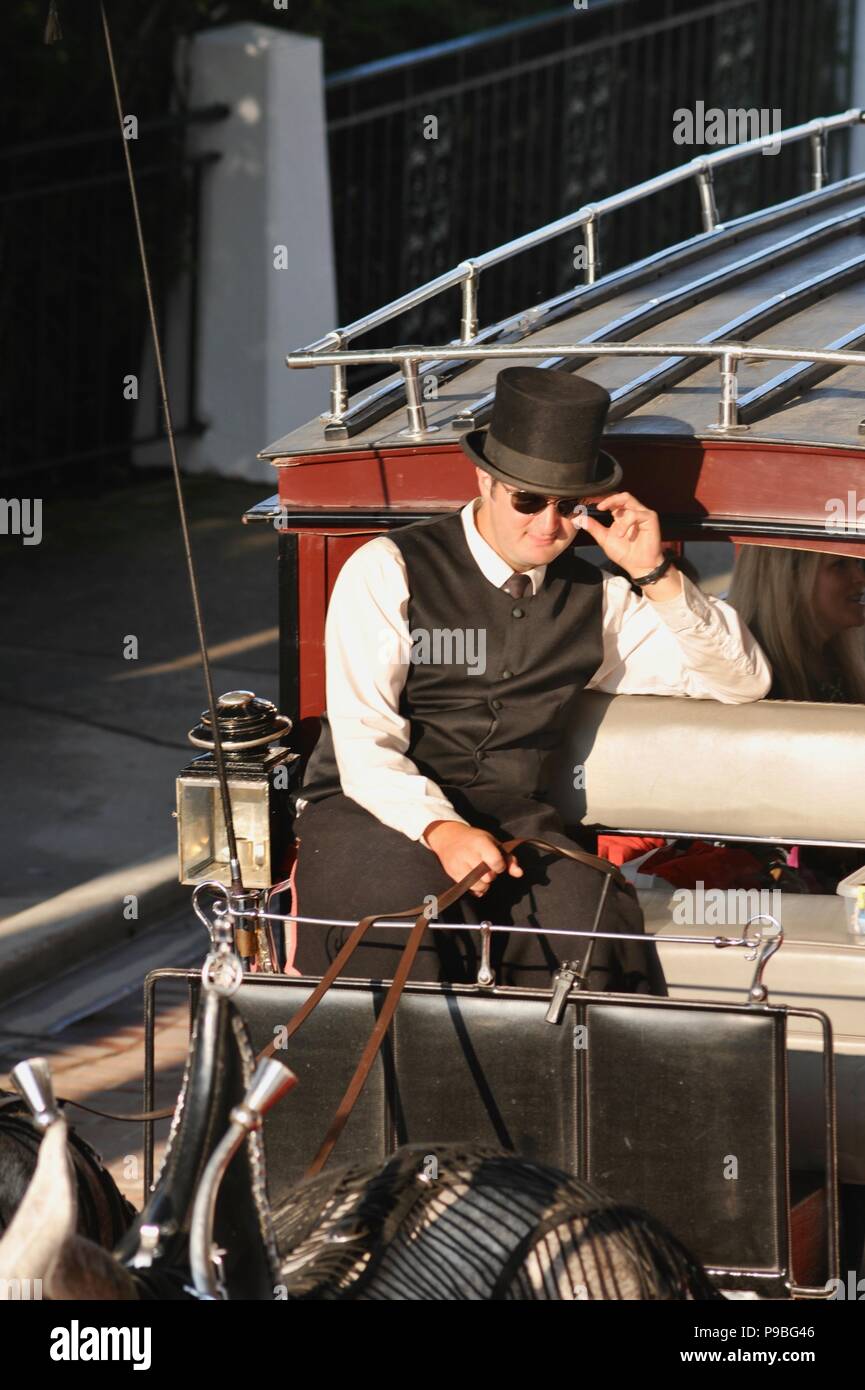 Horse driver (coachman) in black top hat on red, horse drawn carriage ...