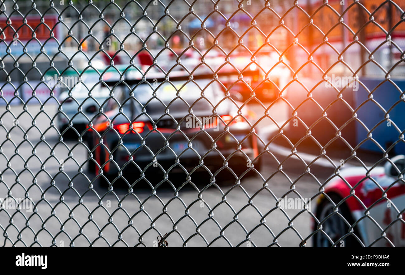 Motor sport car racing on asphalt road. View from the fence mesh ...