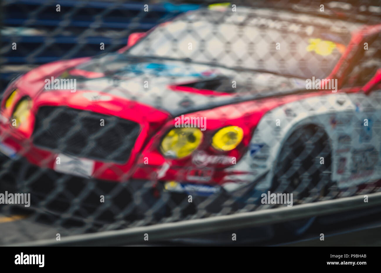 Blurred picture of fence mesh netting and car on racetrack background ...