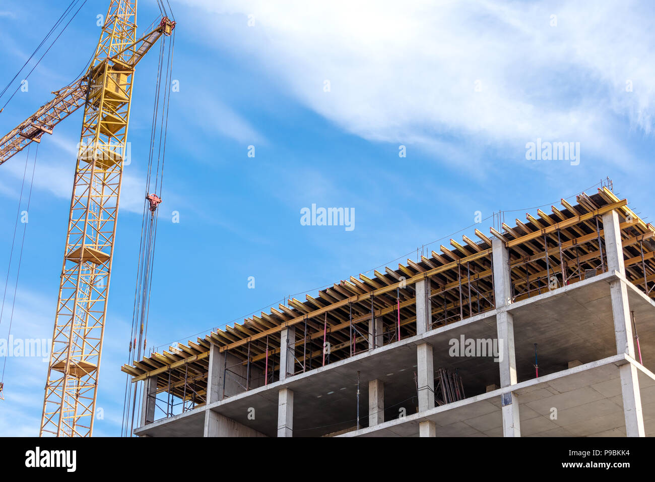 construction site with high-rise building and yellow lift crane against ...