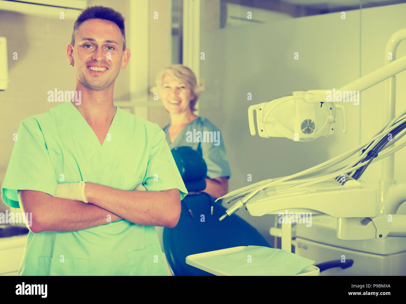 Male dentist standing in dental office with hands crossed looking at ...