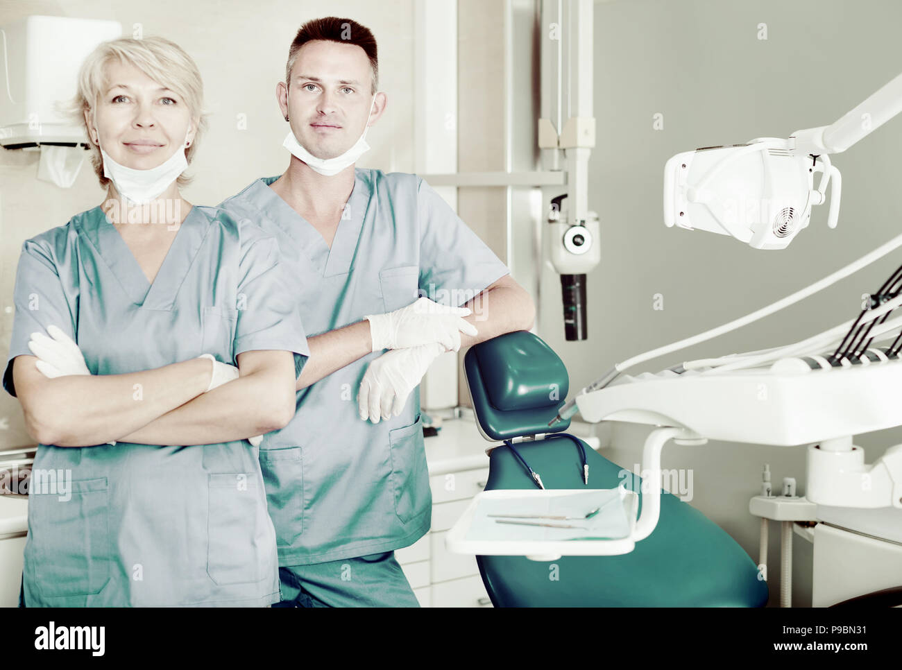 Two professional confident dentists posing near dental chair at clinic ...
