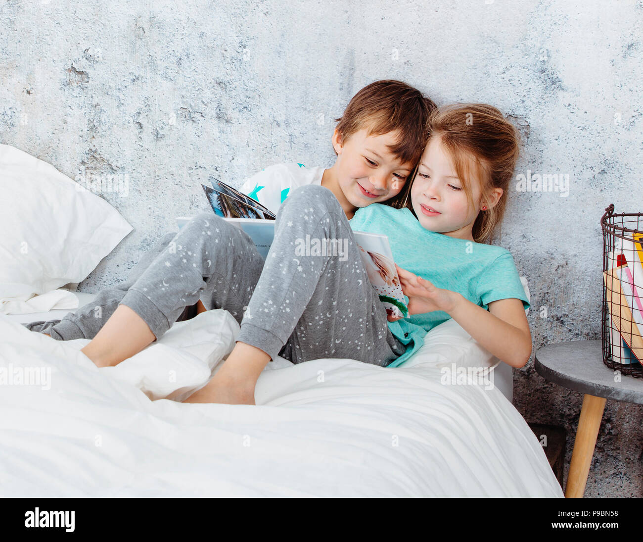 Beautiful Girl is reading a book to her brother in bed Stock Photo - Alamy