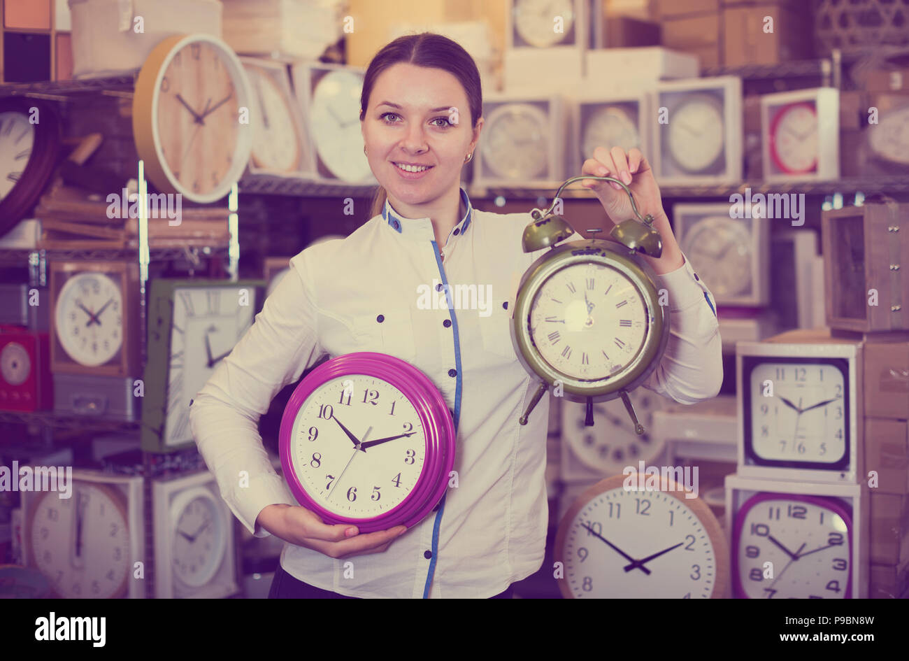 Attractive woman is standing with modern clock in furniture store Stock ...