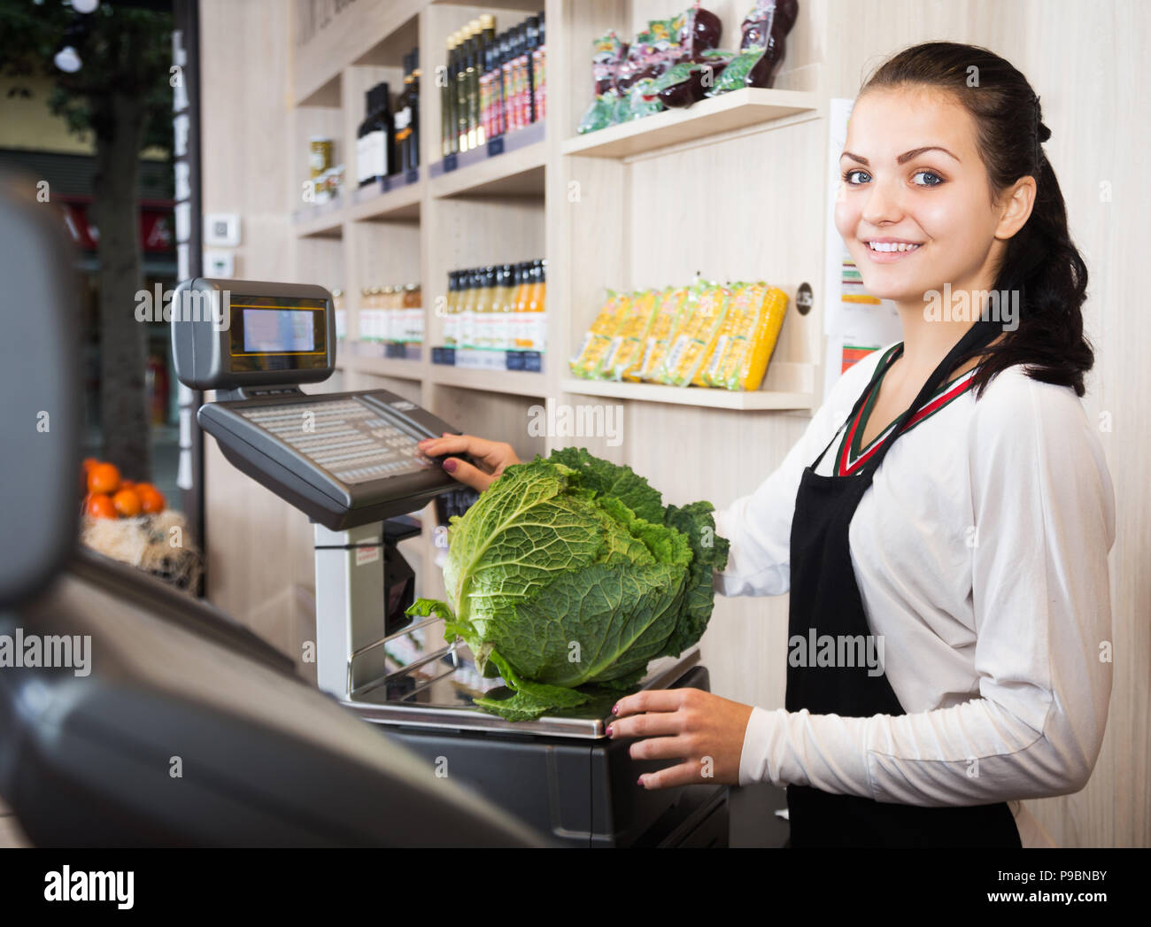 Smiling female seller weighing cabbage in grocery shop Stock Photo - Alamy
