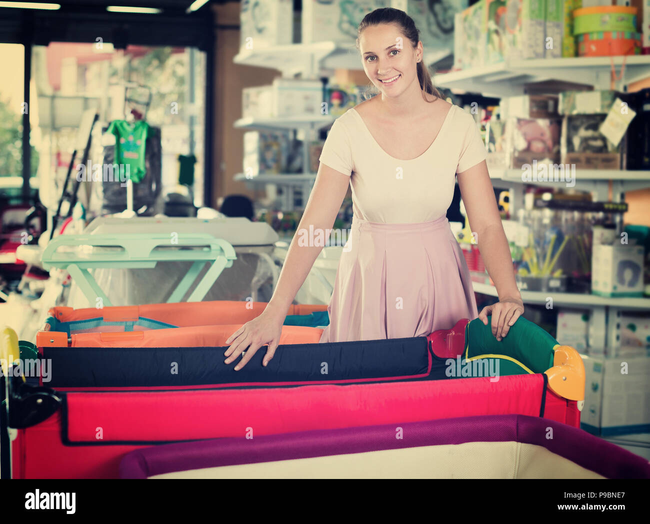 Smiling young pregnant woman choosing playpen for future baby in ...