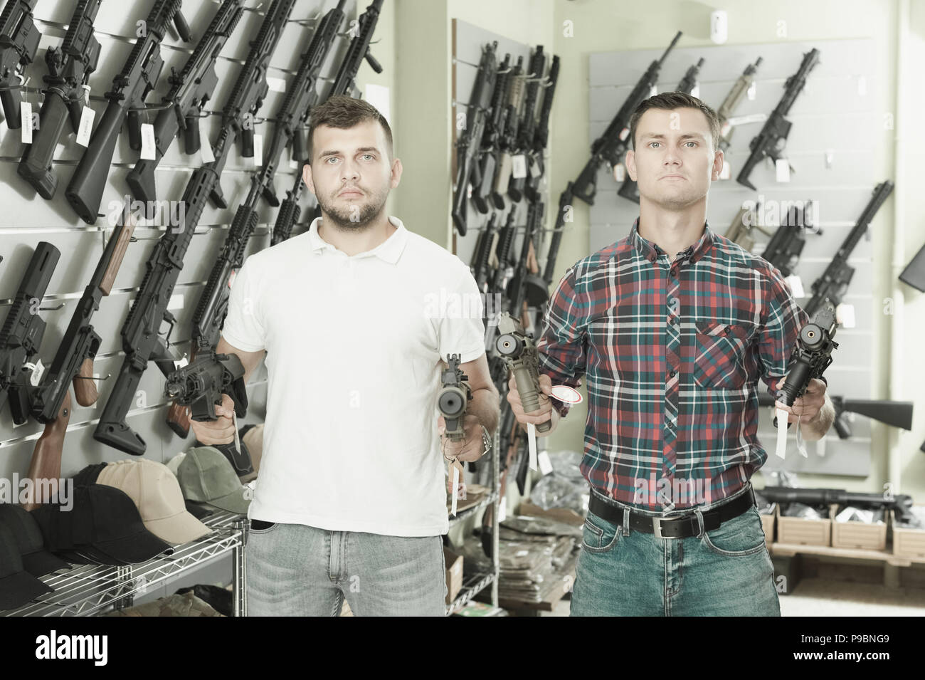 Portrait of two serious young male friends choosing air-powered gun in ...