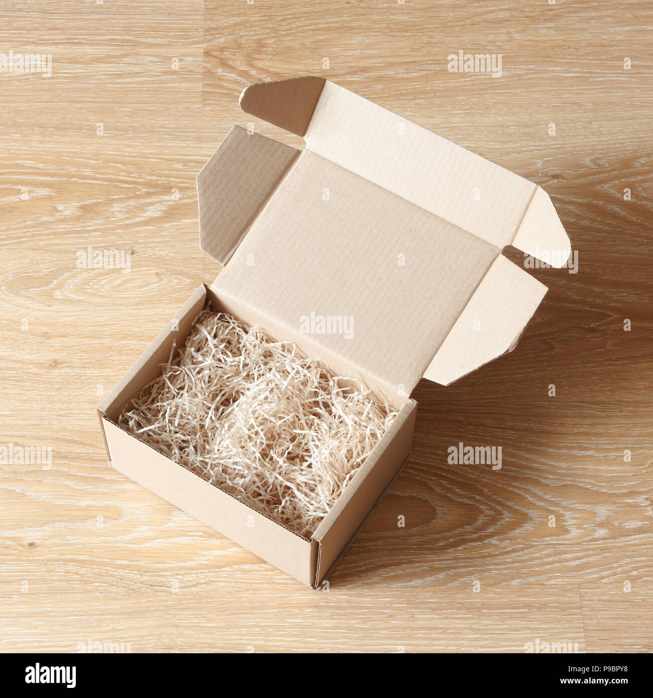 Opened cardboard box with wood excelsior shred filler on wooden ...