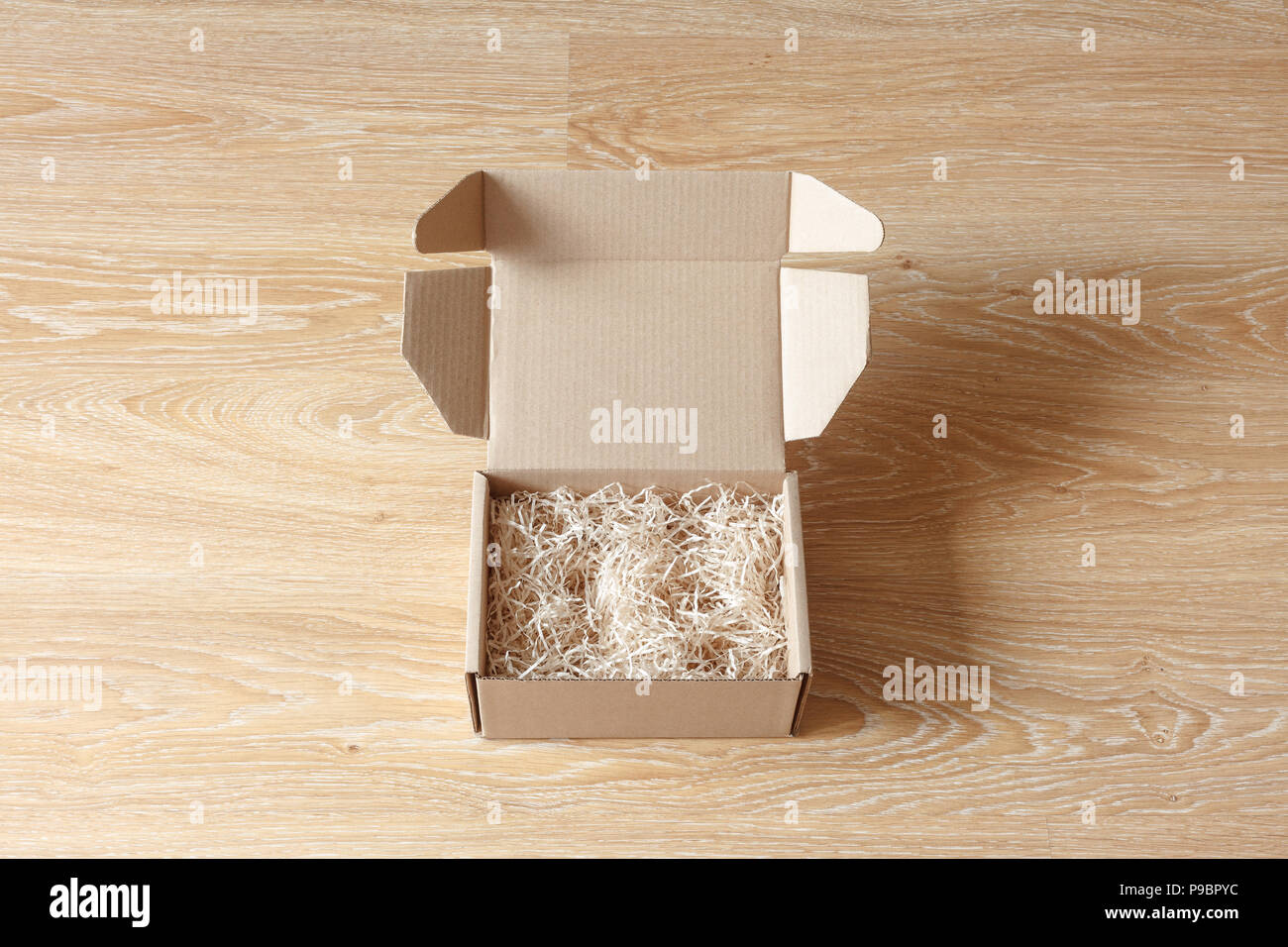 Opened cardboard box with wood excelsior shred filler on wooden ...