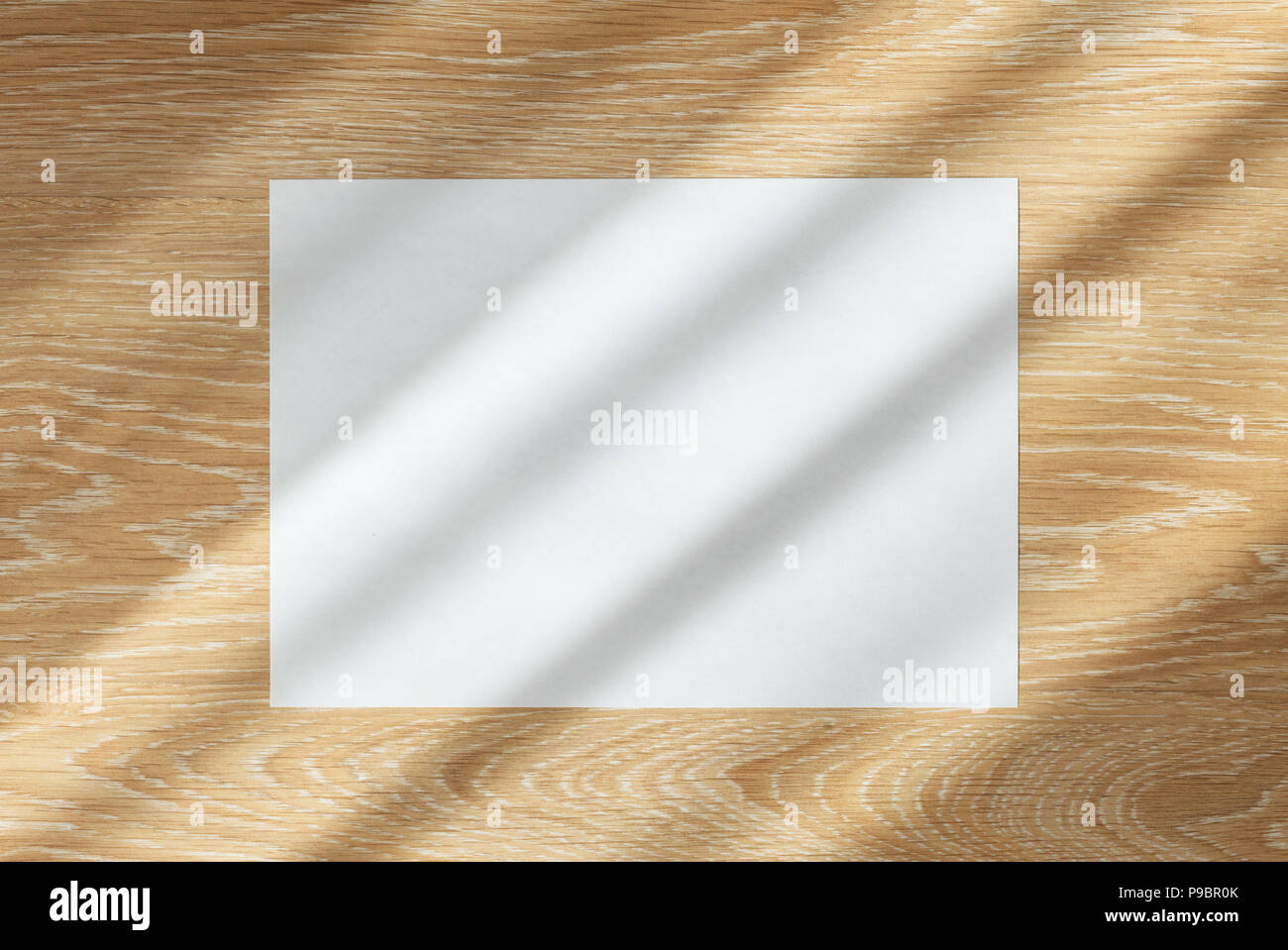 Blank sheet of paper landscape orientation on wooden background in sun ...