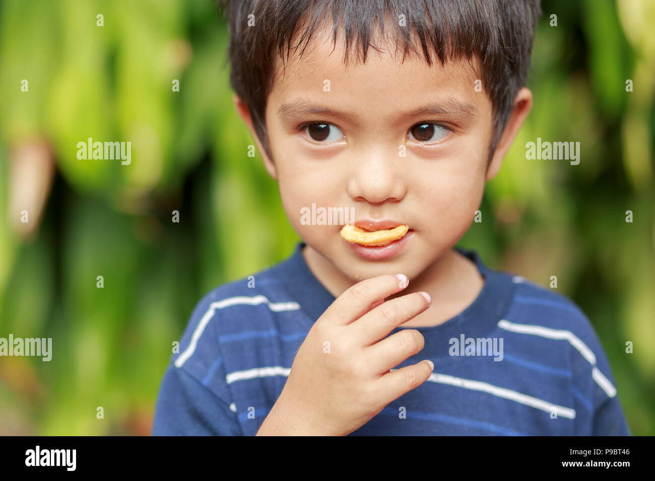 Asian little boy eating fish crisp Stock Photo - Alamy