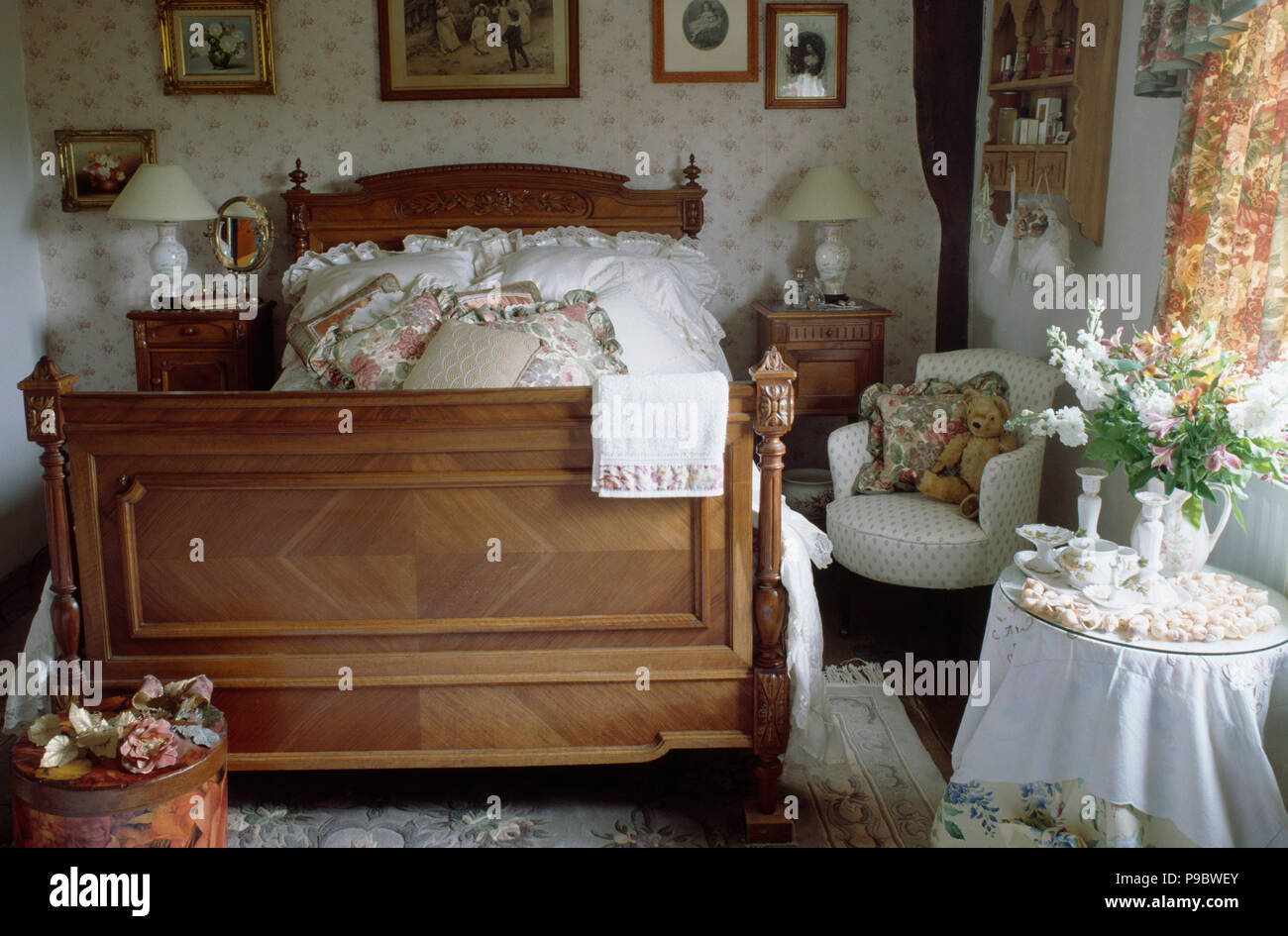 Cushions piled on antique wooden bed in small cluttered bedroom Stock ...