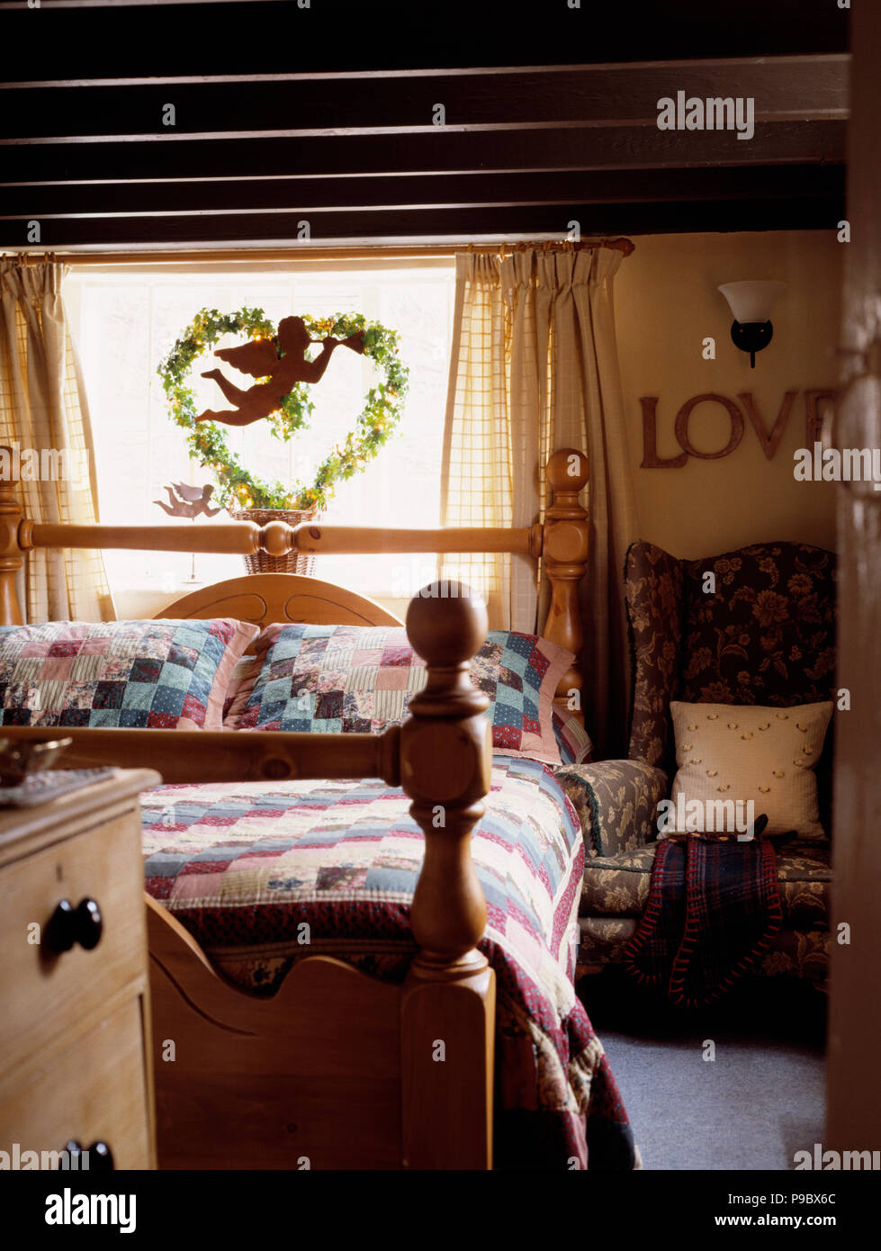 Cupid and heart on window in small cottage bedroom with patchwork quilt ...