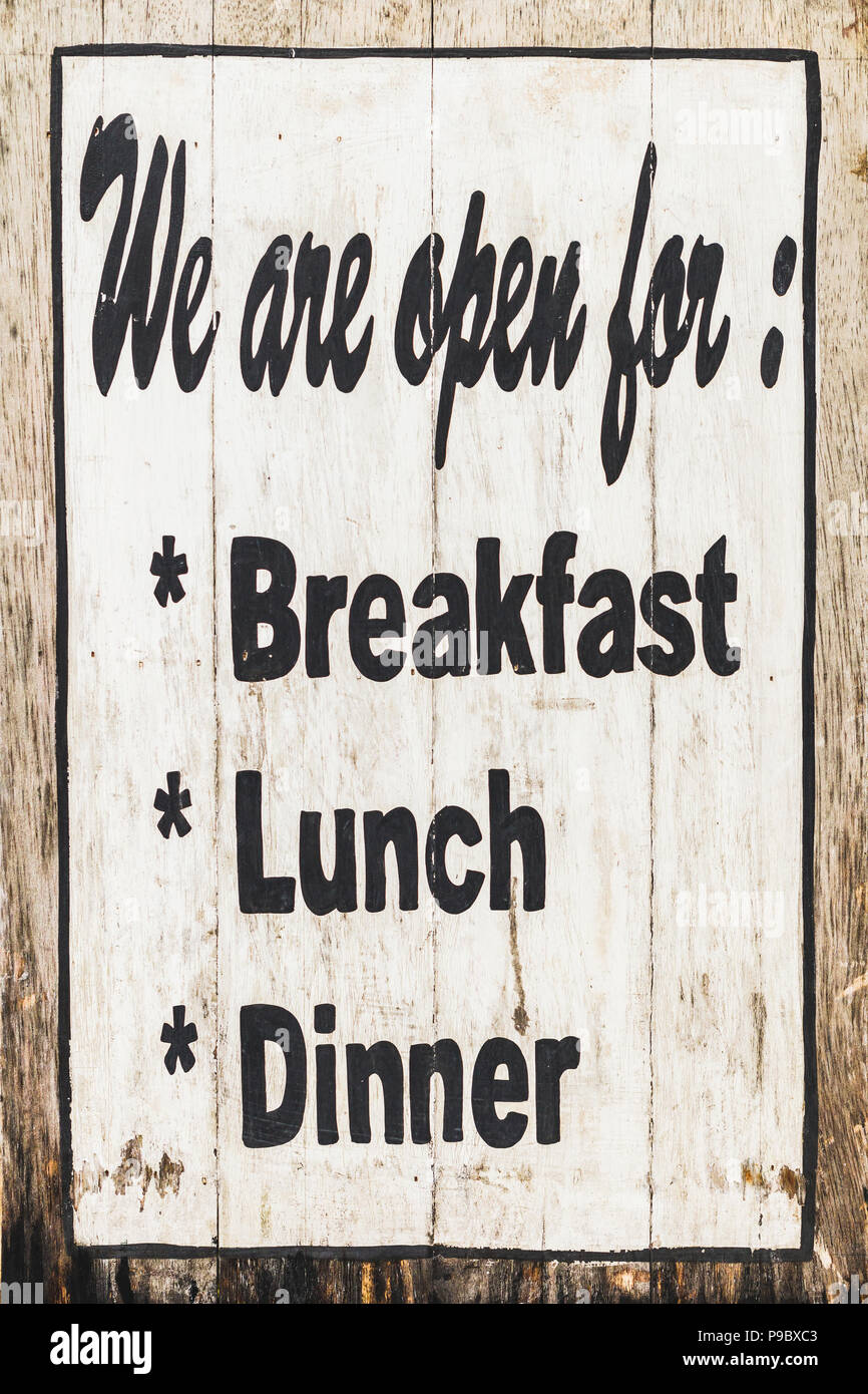 Wooden textured board with painted handwritten black text "We are open ...