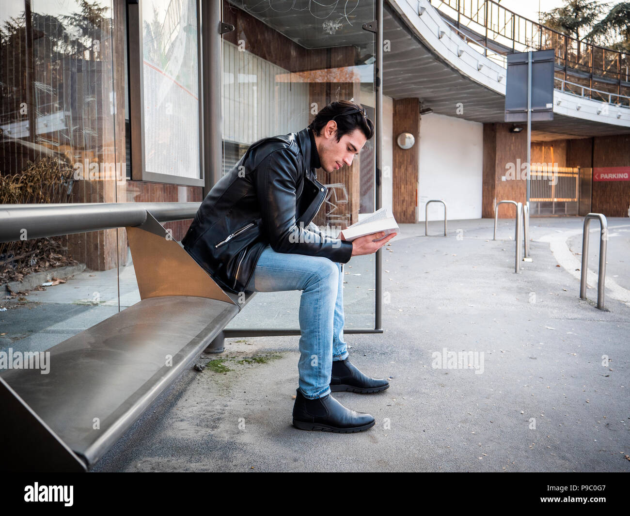 Casual man reading book on bench Stock Photo - Alamy