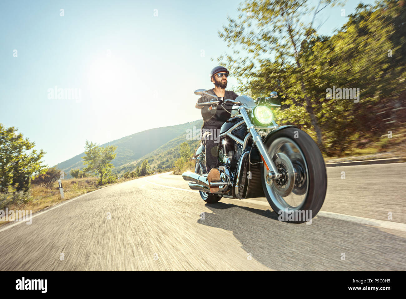Biker riding a motorcycle on open road Stock Photo - Alamy
