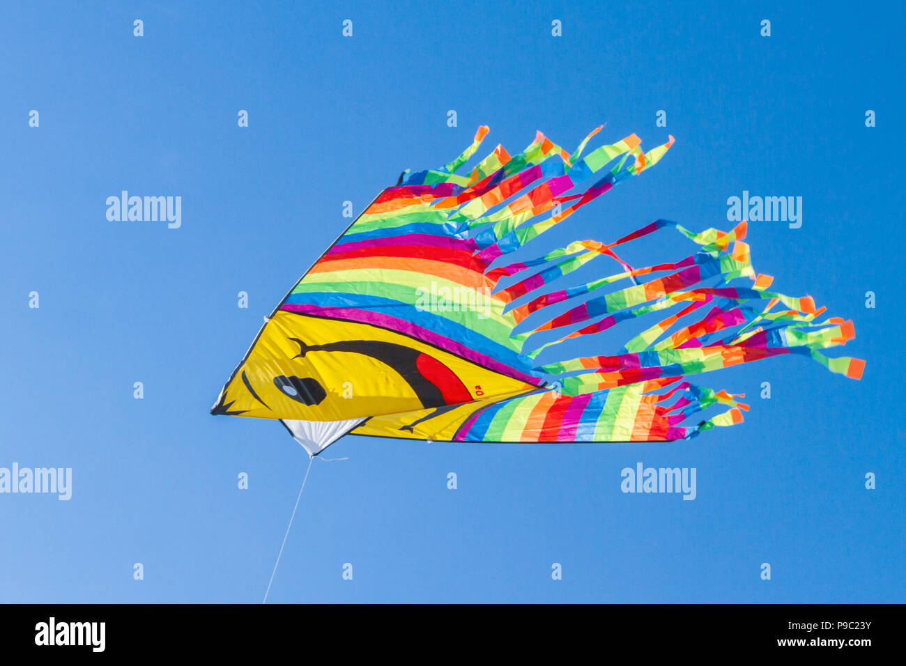 A fun and bright flying kite in the blue sky Stock Photo - Alamy