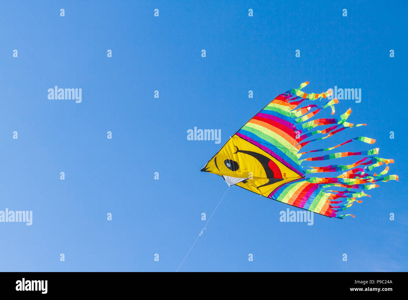 A fun and bright flying kite in the blue sky Stock Photo - Alamy