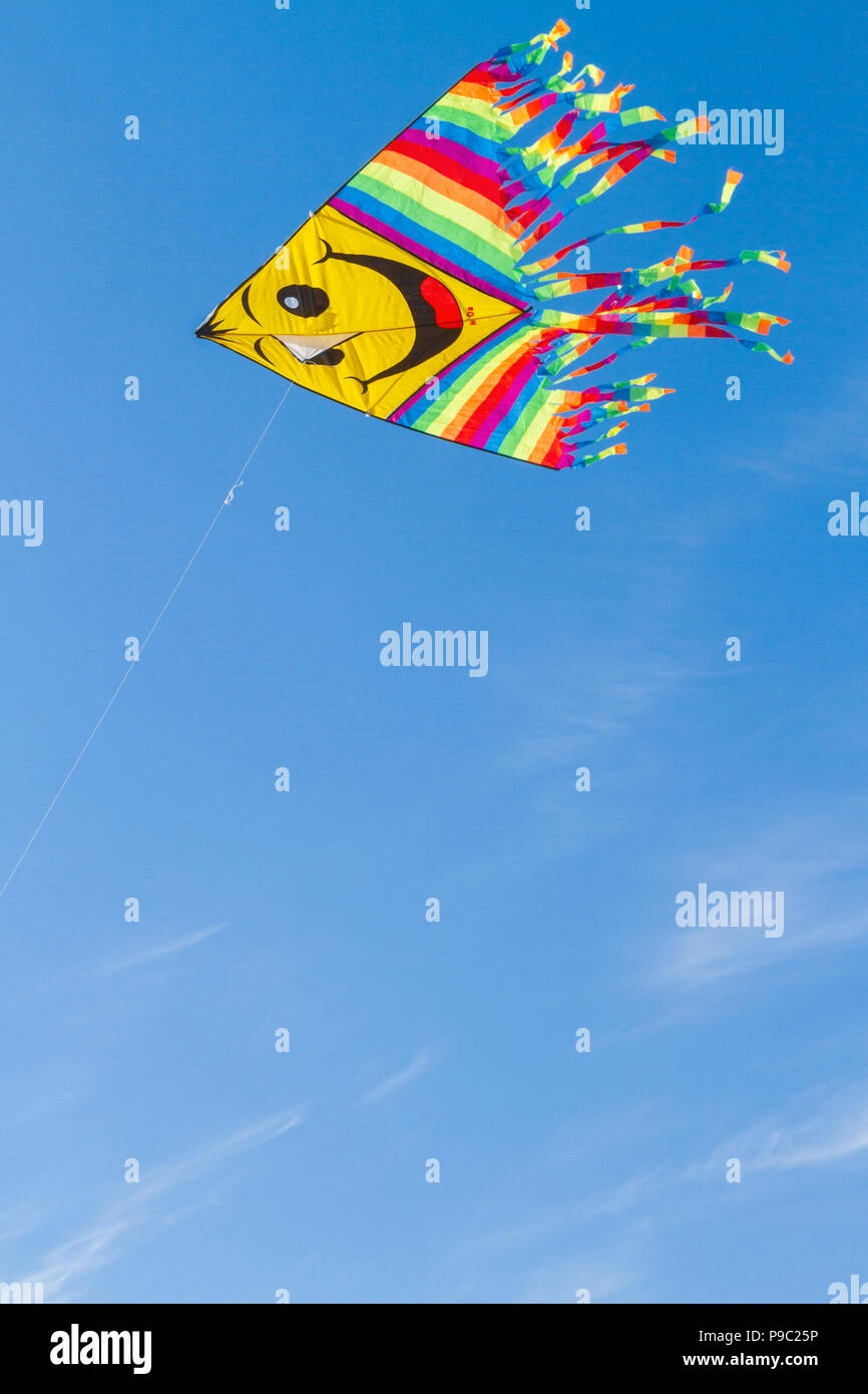 A fun and bright flying kite in the blue sky Stock Photo - Alamy