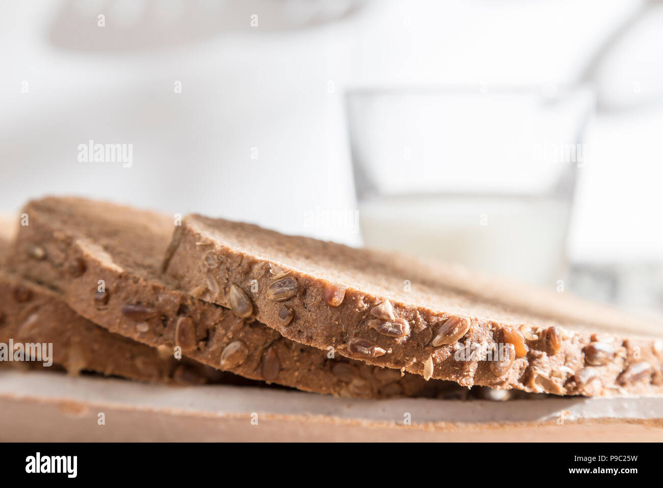 glass of milk and tray with several slices of wholemeal rye bread with ...