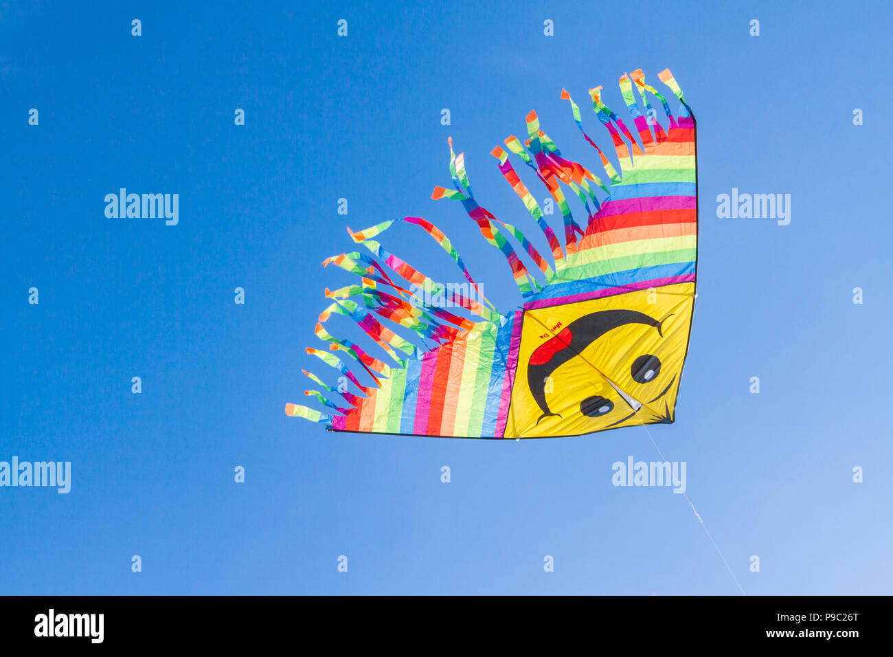 A fun and bright flying kite in the blue sky Stock Photo - Alamy